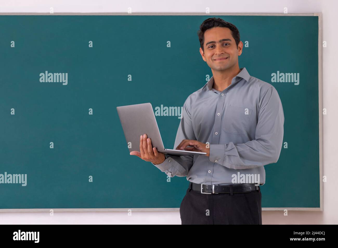 Portrait of a young school teacher using laptop in classroom Stock ...
