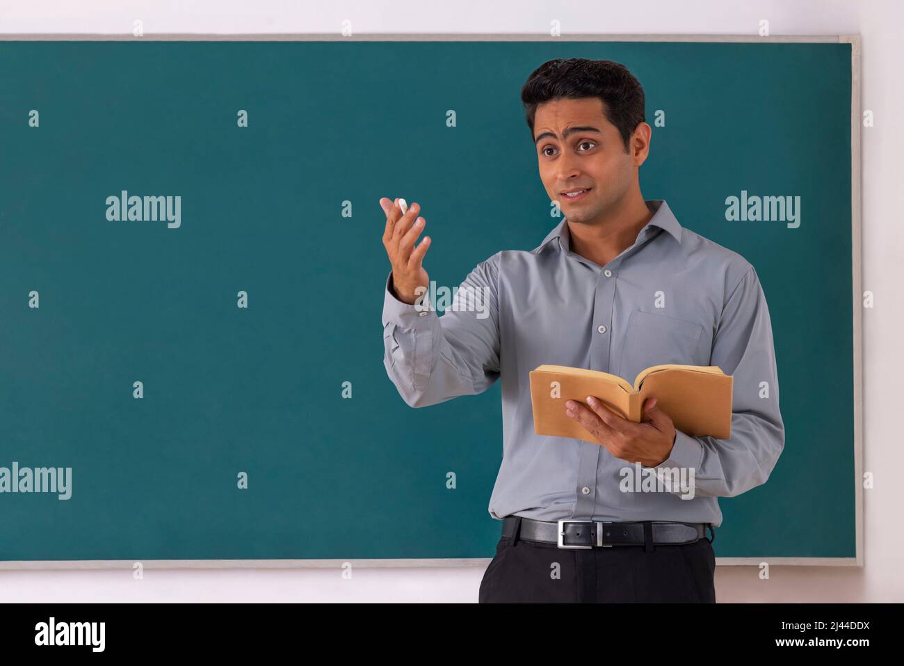 School teacher teaching in front of blackboard in classroom Stock Photo ...