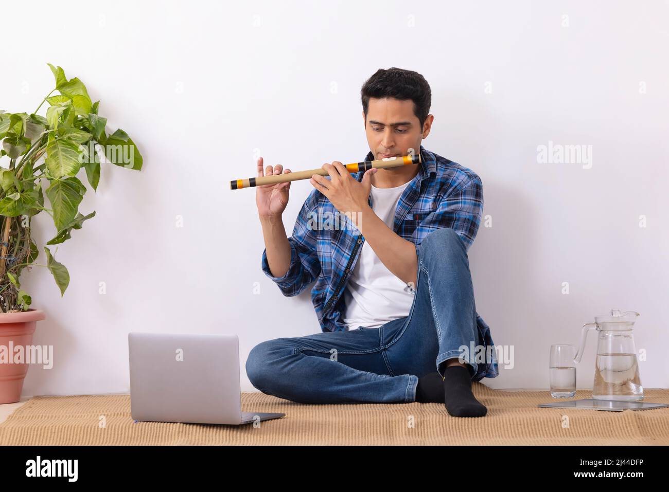 Young music teacher playing flute during online class in living room ...