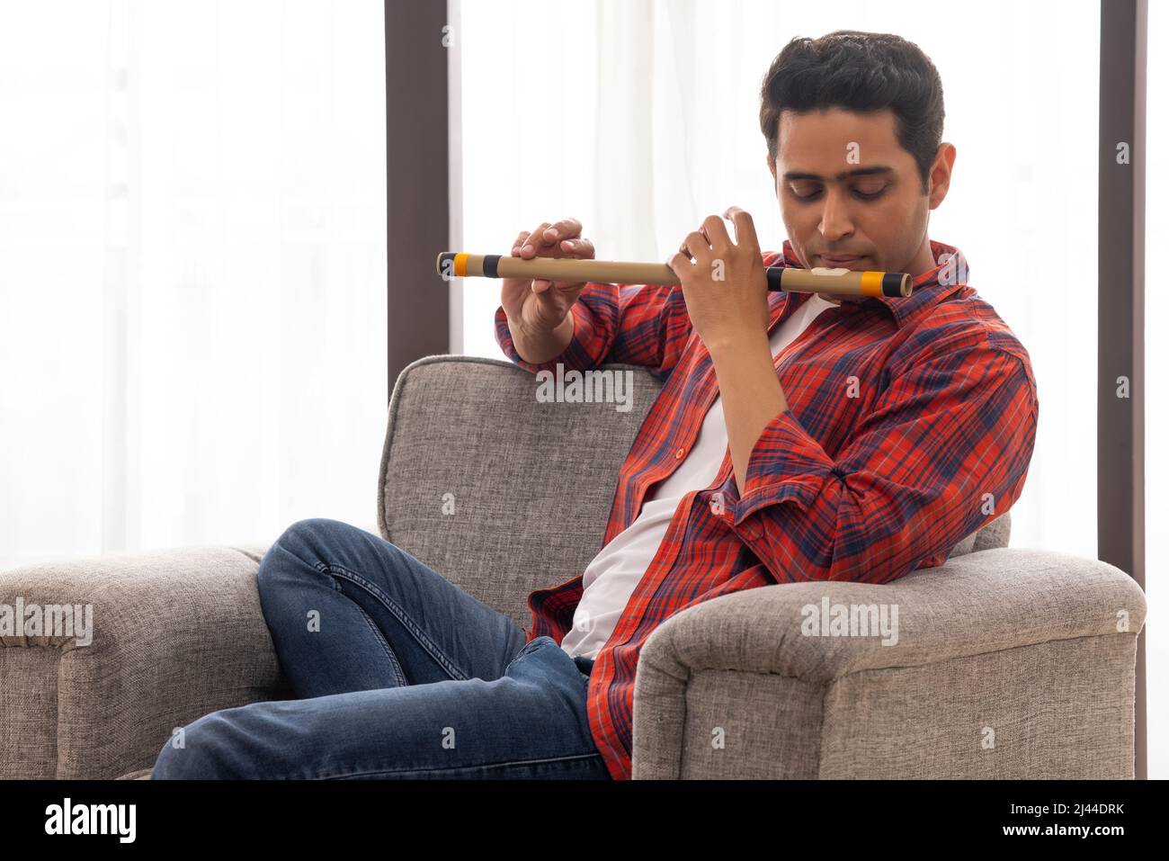 Portrait of a young musician playing flute in living room Stock Photo ...