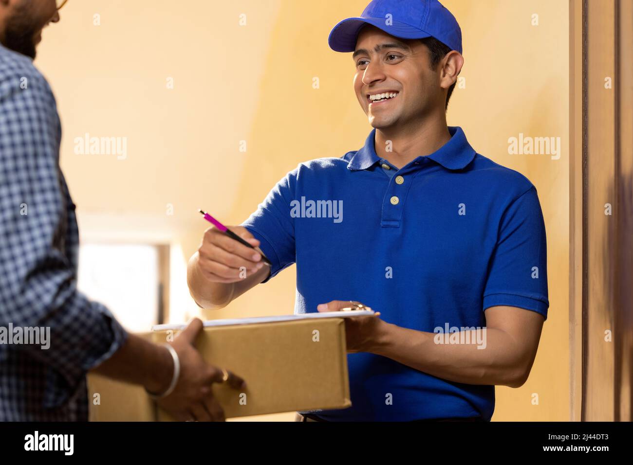 Young delivery boy requesting customer to sign receipt after receiving ...