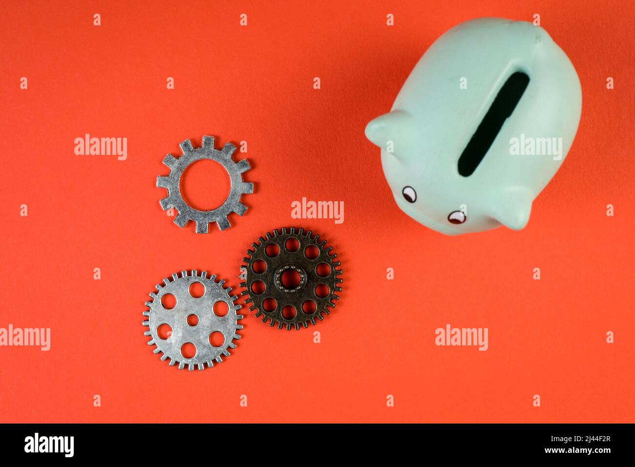 Gears and piggy bank on a red background. Money saving concept Stock ...
