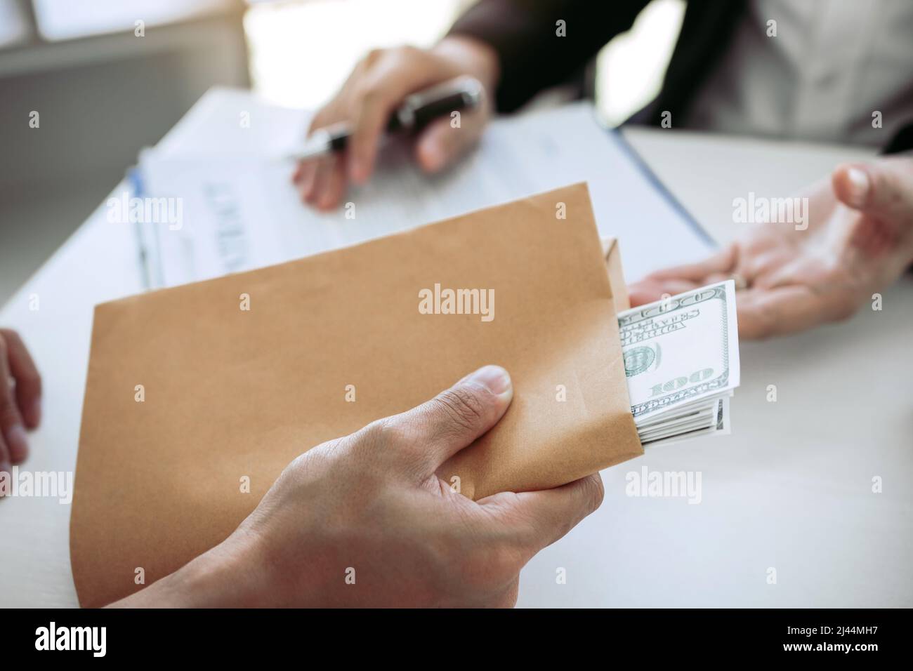 Businessman secretly giving a bribe by giving money bills in envelope ...