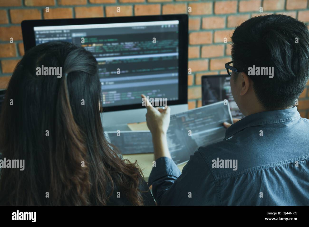 Two software developers are using computers to work together with their ...