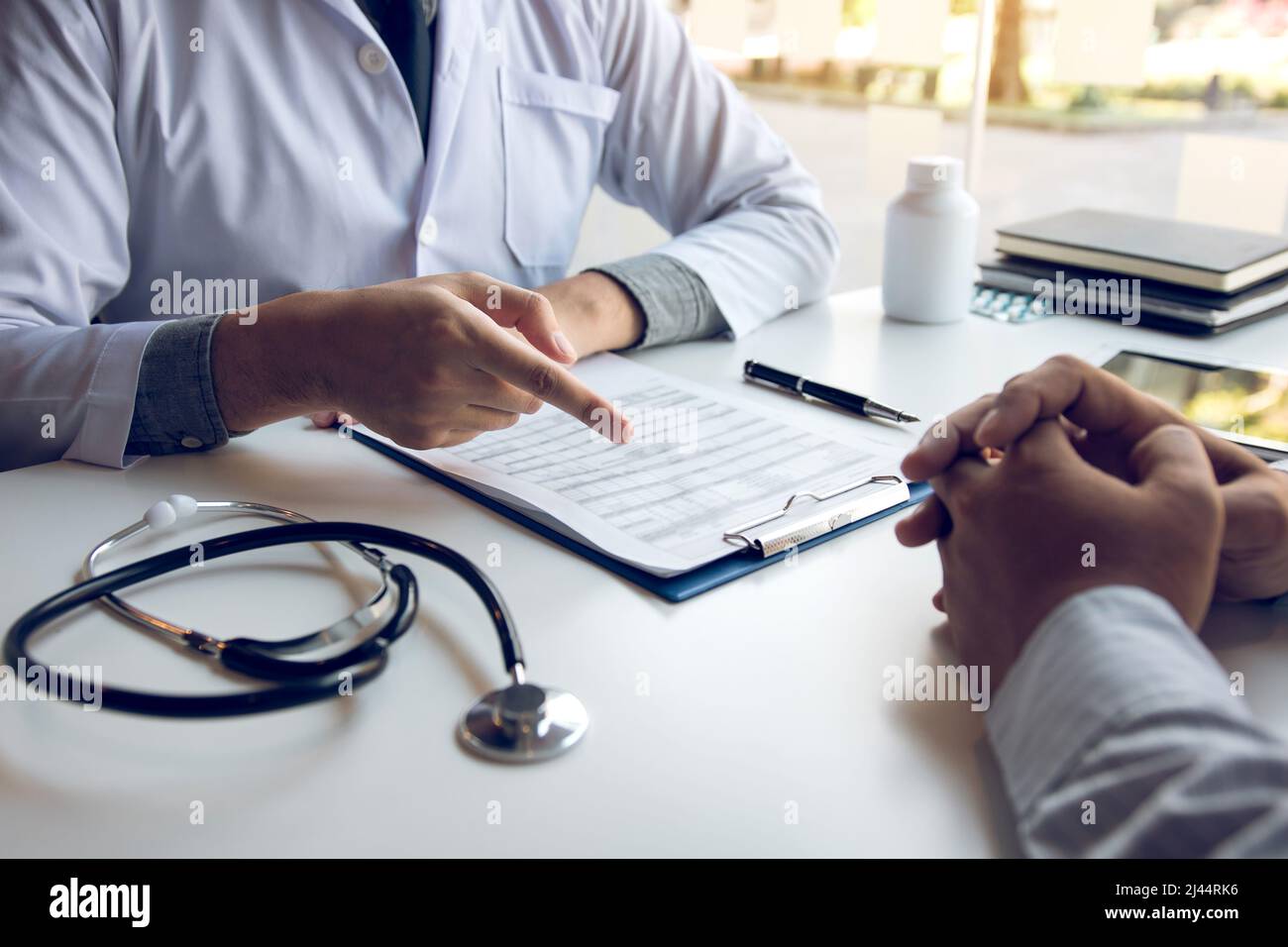 Male patient listening to doctor at desk and consulting with healthcare ...
