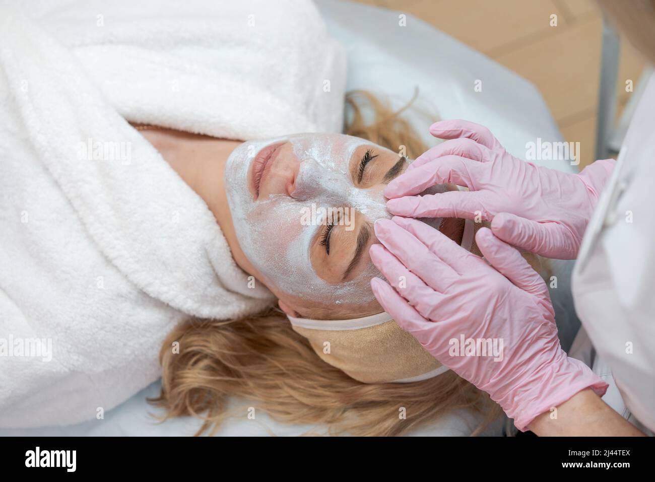 Facial peeling mask, beauty spa, skin care. Woman getting facial treatment by beautician at SPA ...