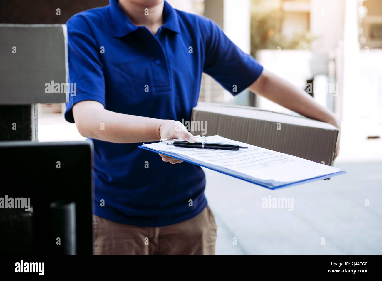 Young asian man smiling while delivering a cardboard box to the woman ...