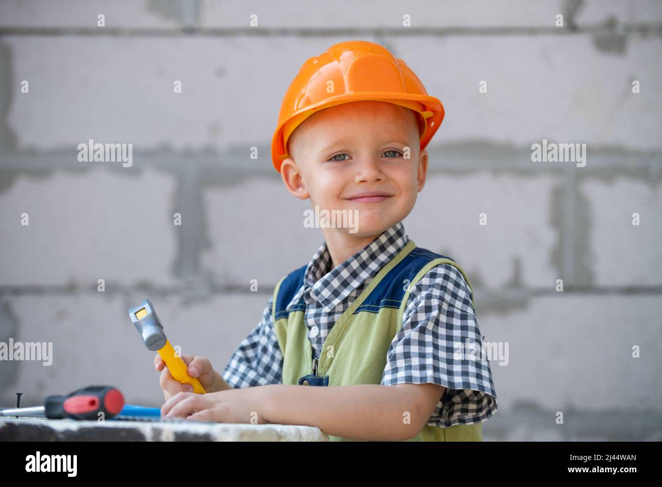 Cute little kid in builder helmet with repair tools on construction ...