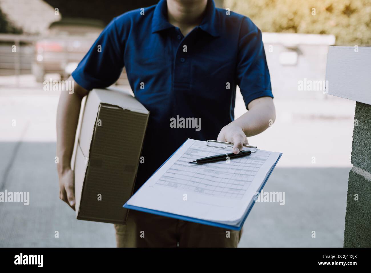 Young asian man smiling while delivering a cardboard box to the woman ...