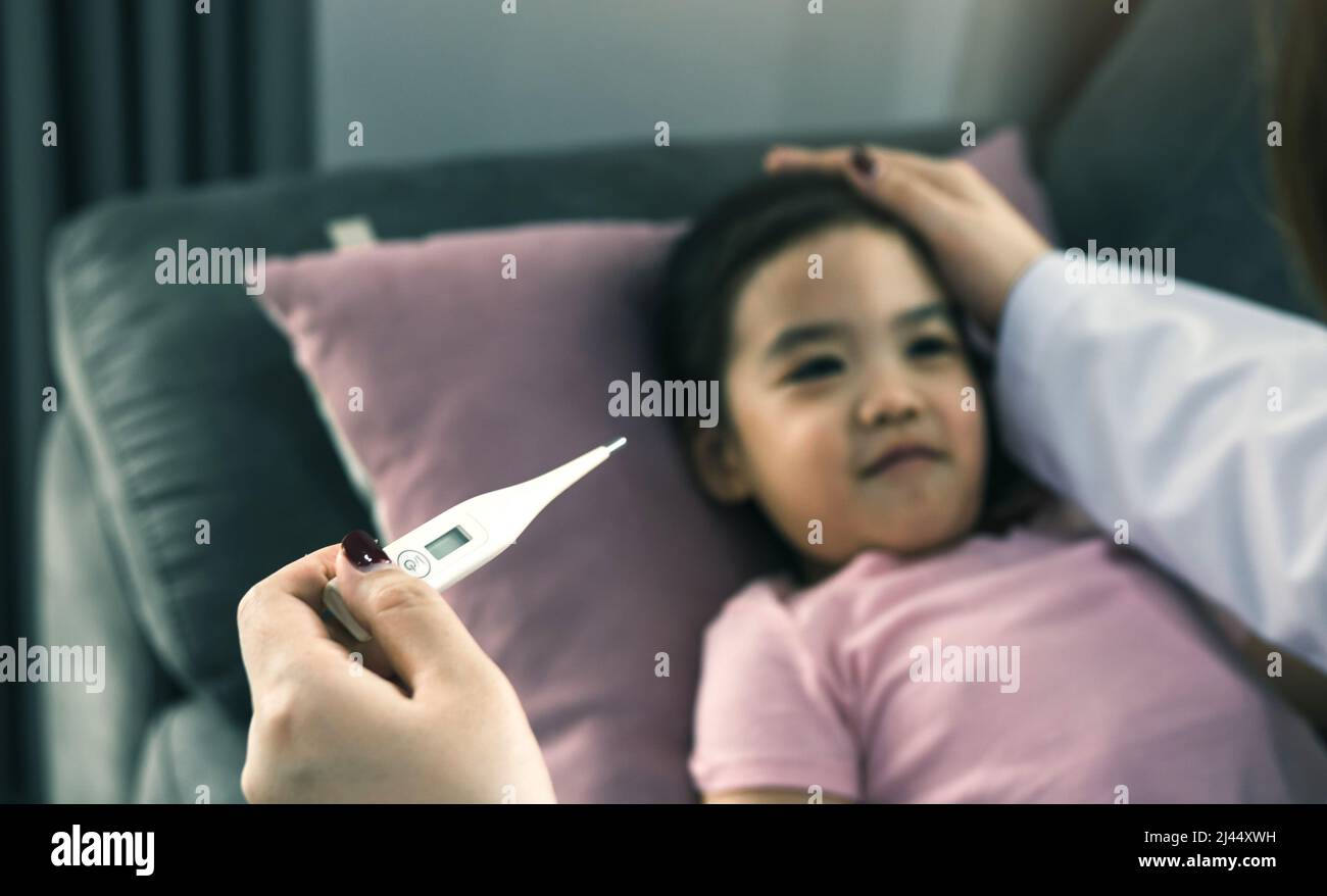 Asian female pediatrician is using a thermometer to measure fever for ...