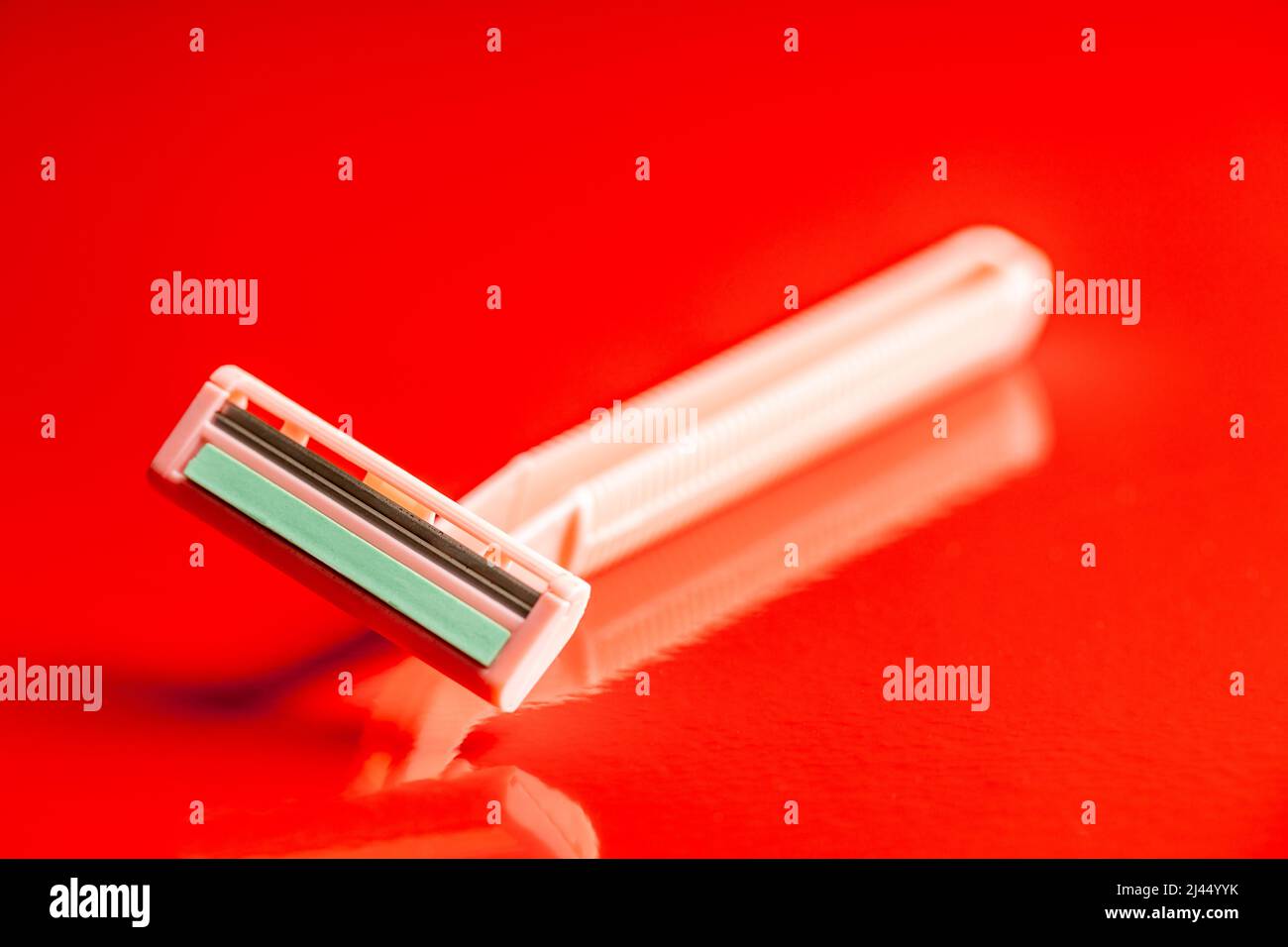 Pink women's razor on a red background Stock Photo - Alamy