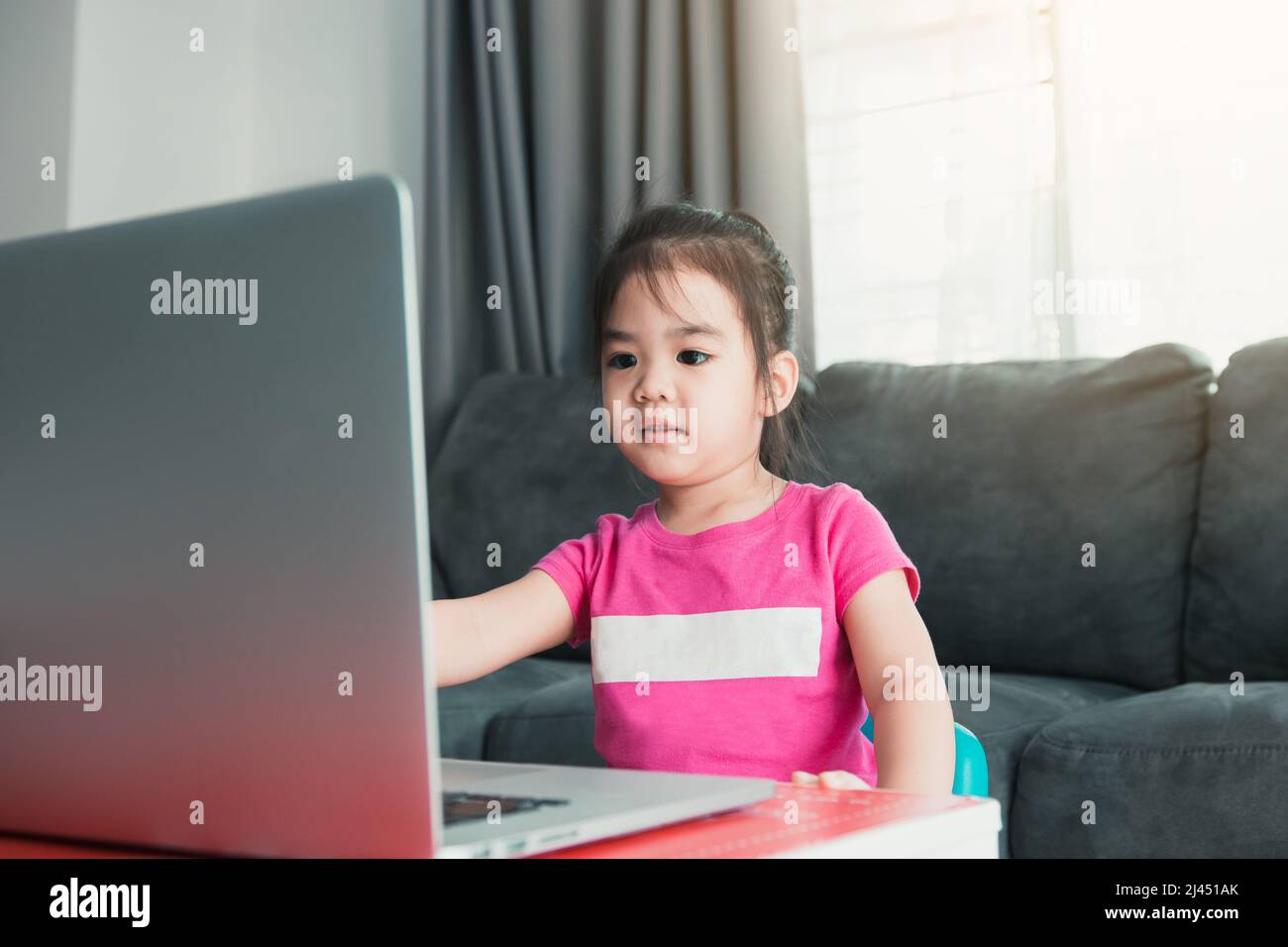 Little girl sitting learning on table working on laptop computer ...