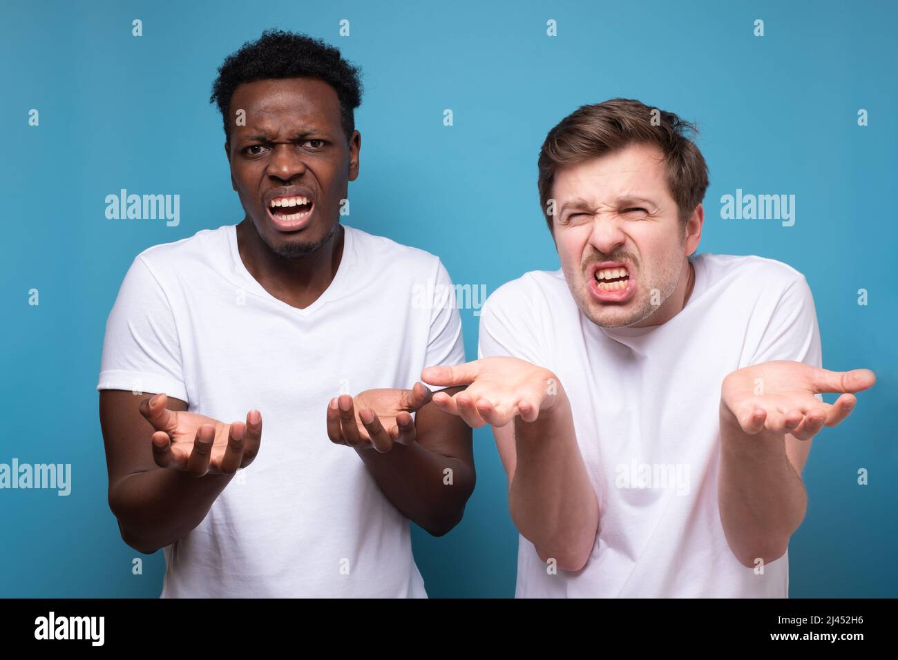 Crazy outraged young men screams loudly and gestures angrily yells ...