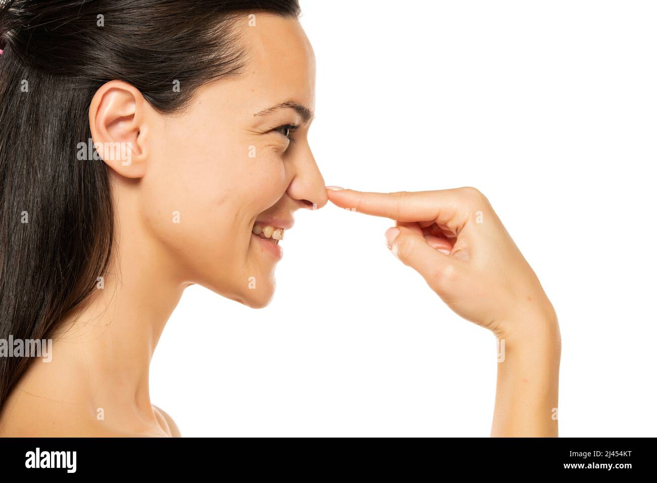 young happy woman touches her nose with her finger on a white ...