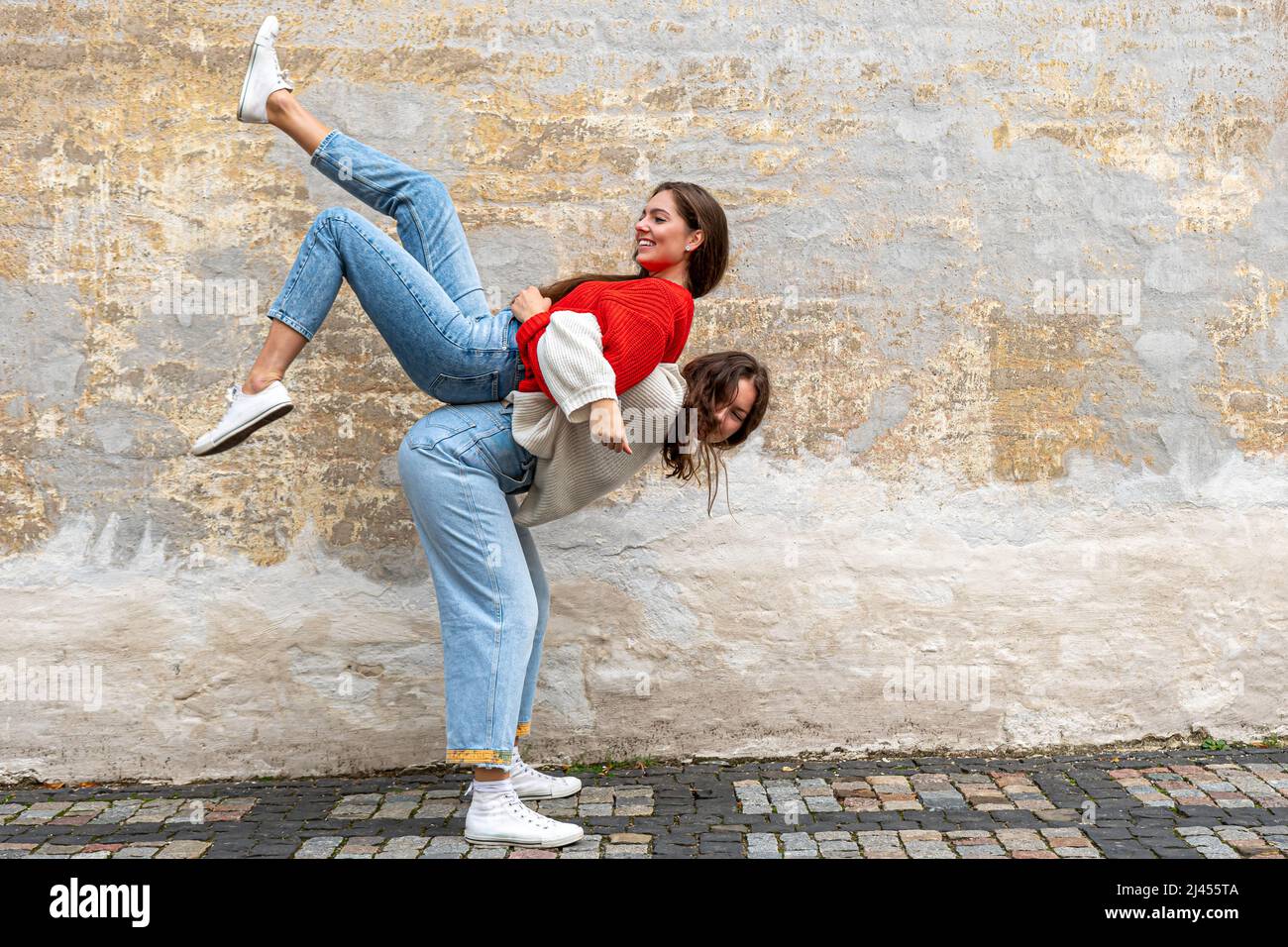 funny teenager carrying her best friend piggyback on the pavement at ...