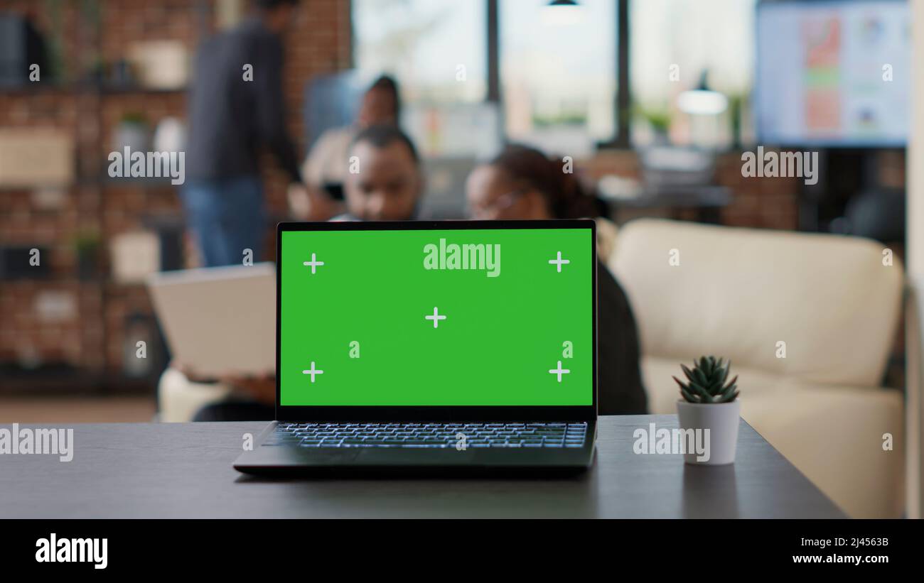 Laptop with green screen display on desk in business office, team of ...