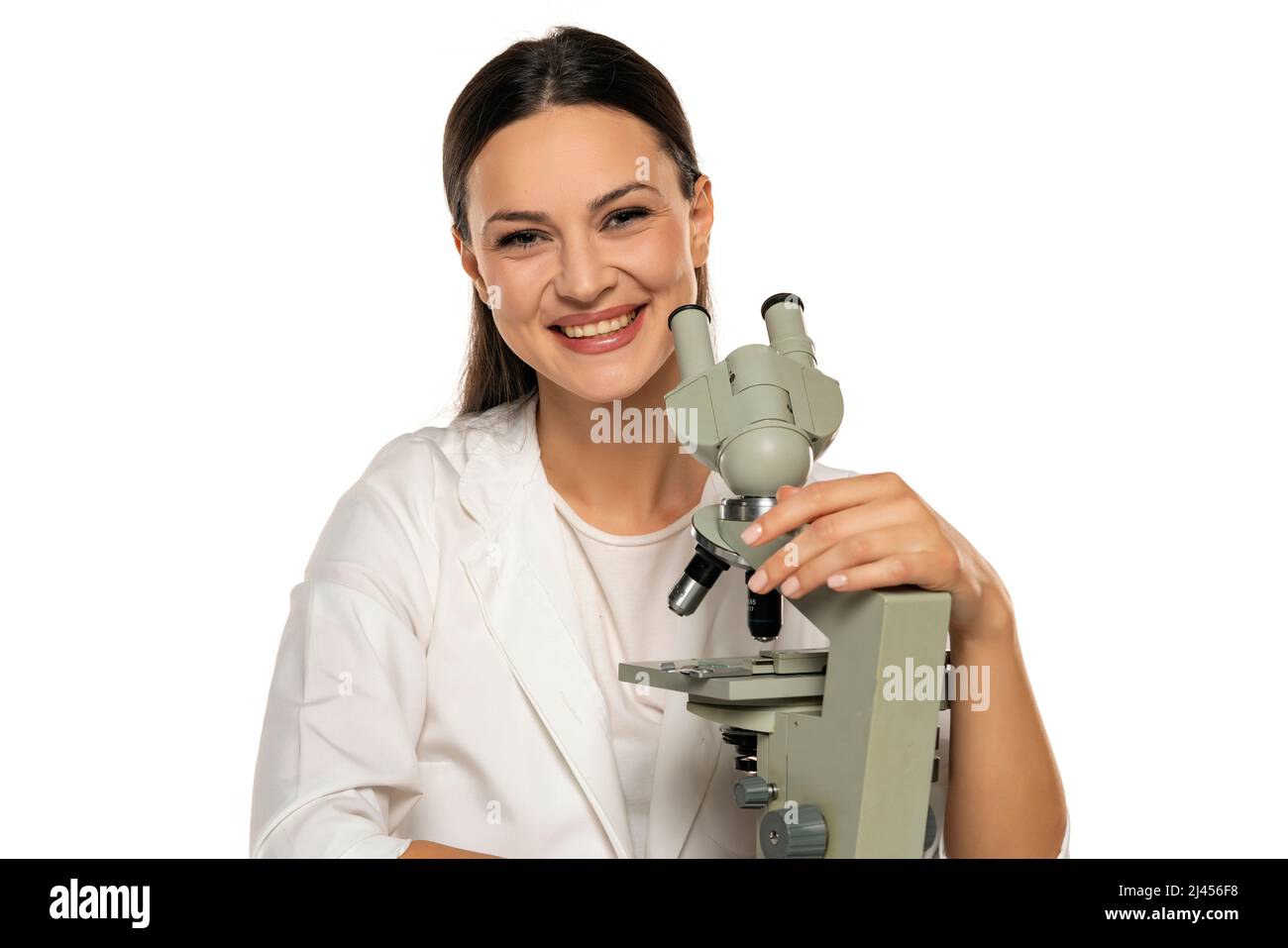 Portrait of smiling female scientist with microscope on a white ...