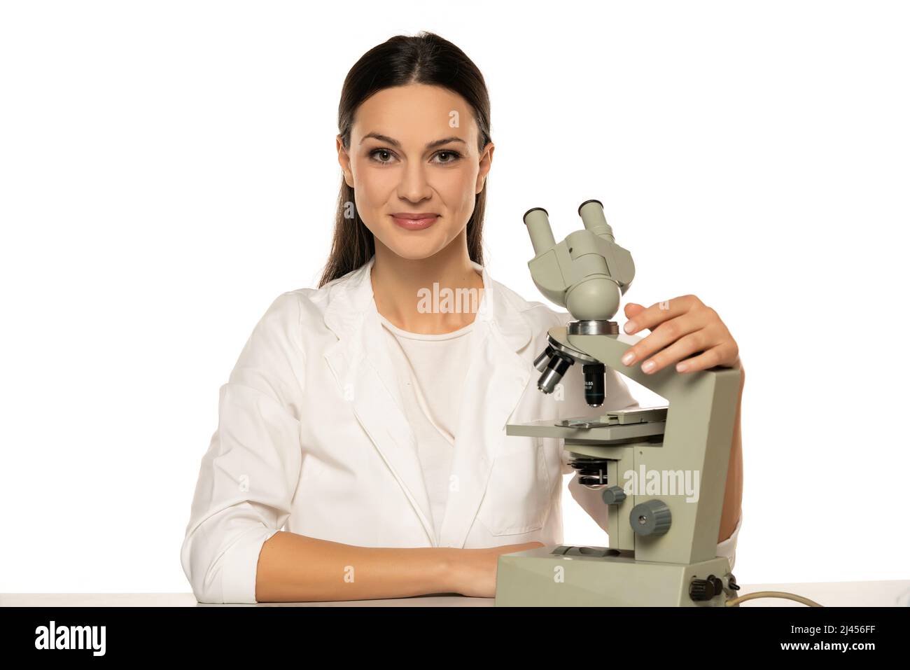Portrait of female smiling scientist with microscope on a white ...