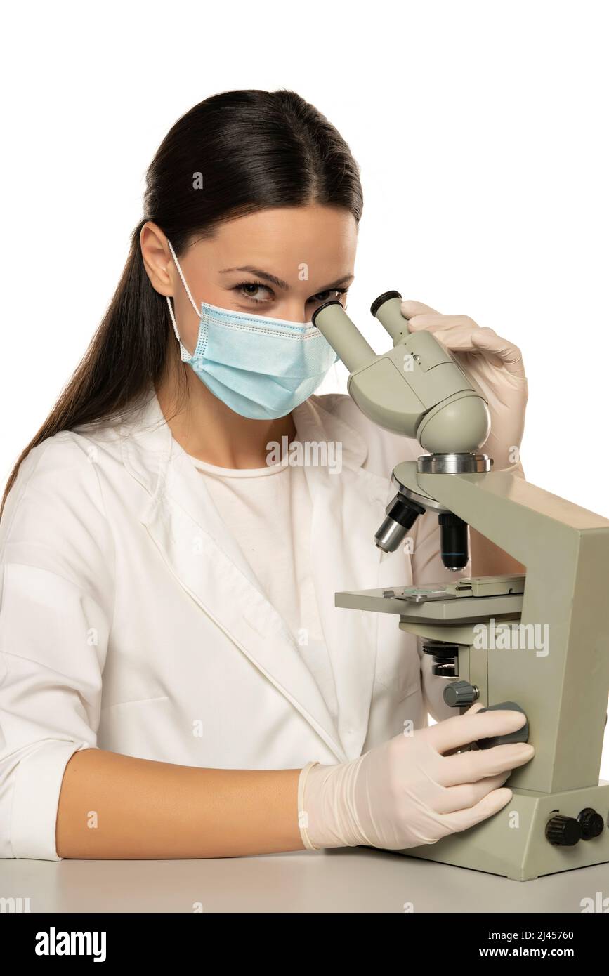Portrait of smiling female scientist with microscope and protective fce ...