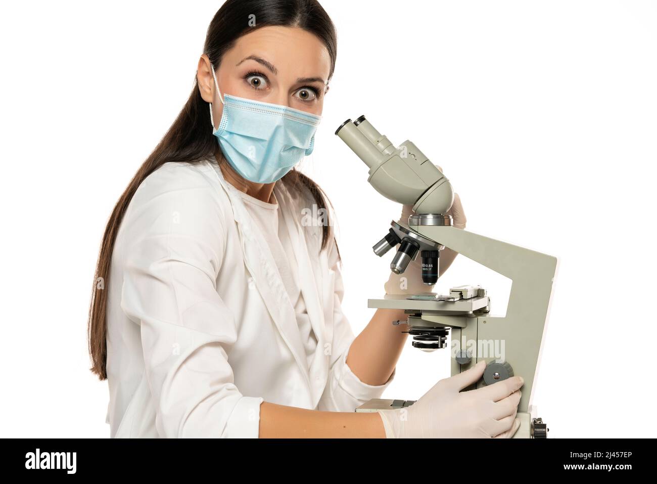 Portrait of shocked female scientist with microscope on a white ...