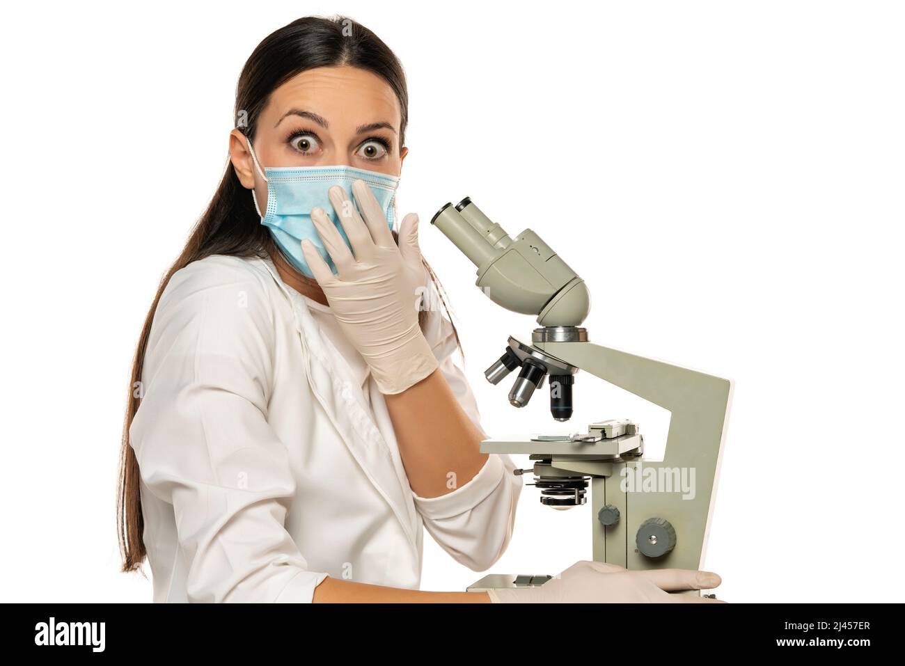 Portrait of shocked female scientist with microscope on a white ...