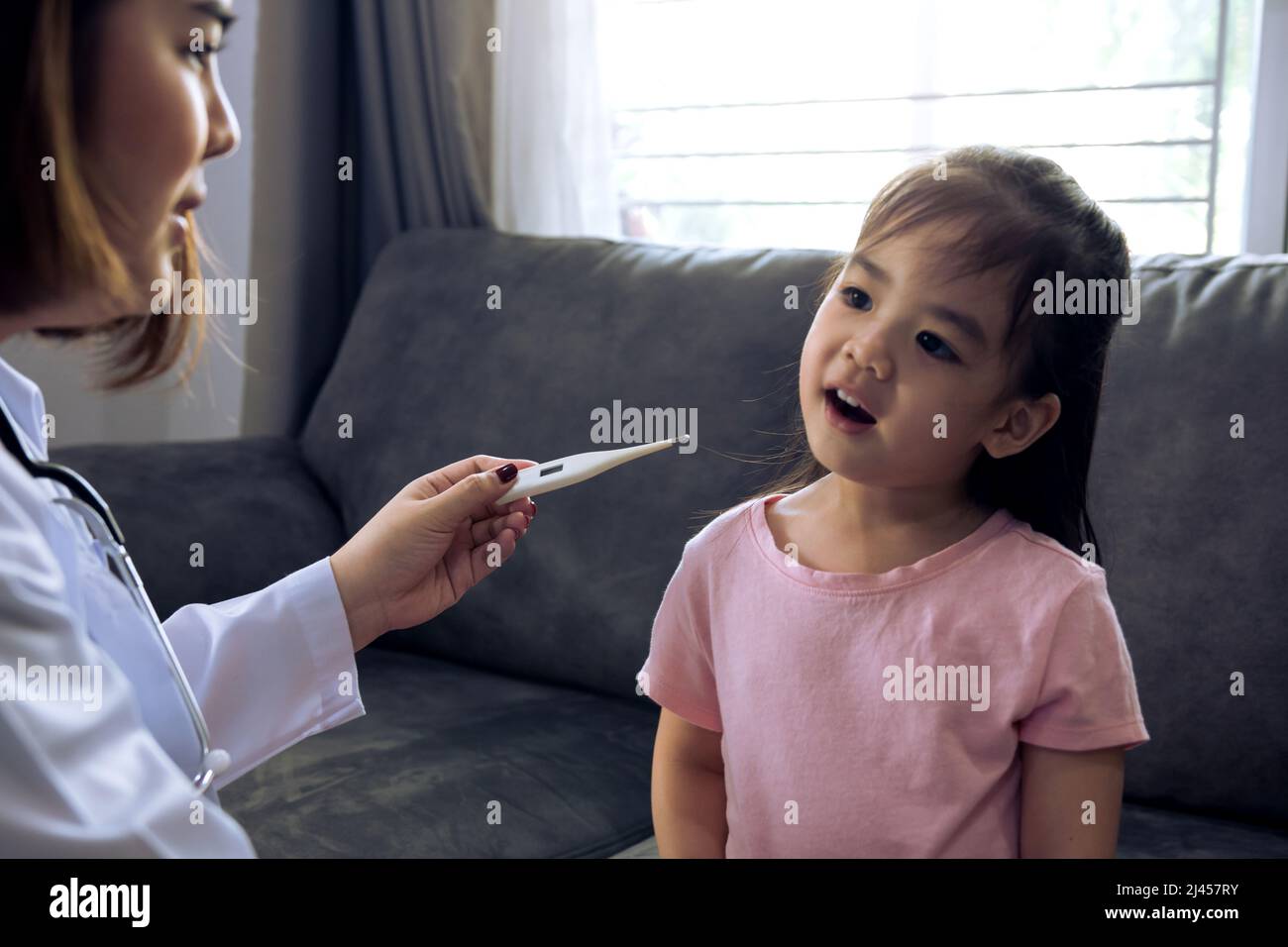 Doctor using temperature child patient in home Stock Photo - Alamy