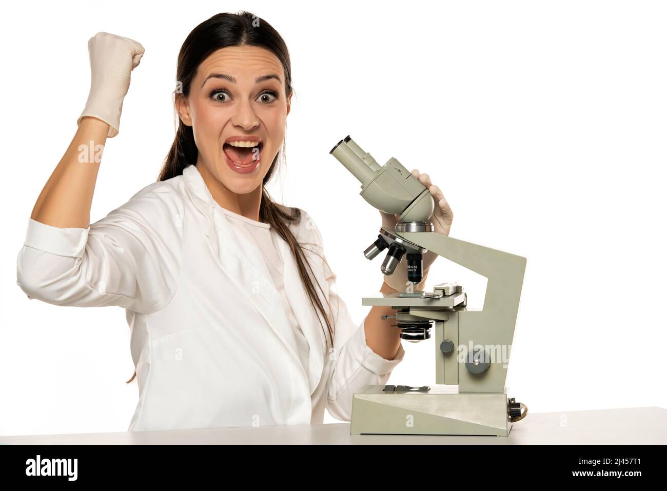 Portrait of happy female scientist with microscope with winning gesture ...