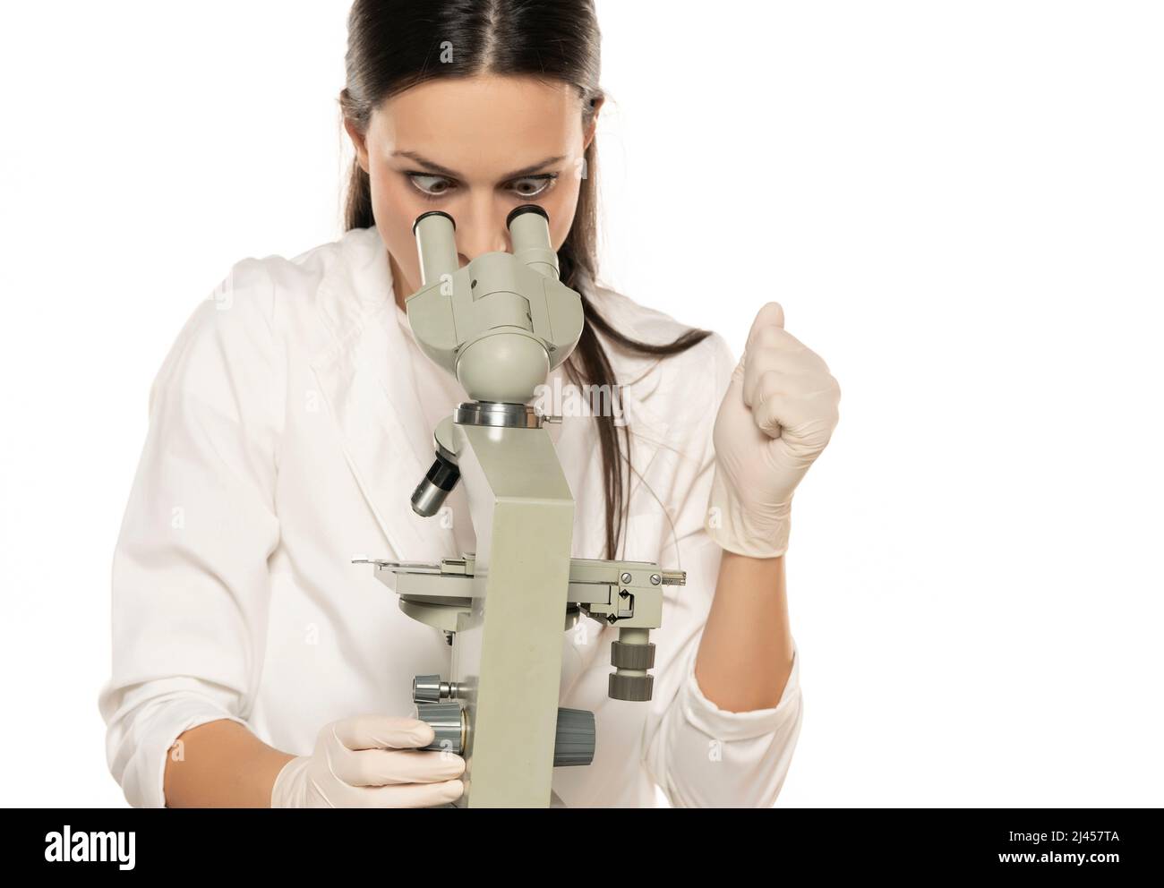 Portrait of shocked female scientist with microscope on a white ...