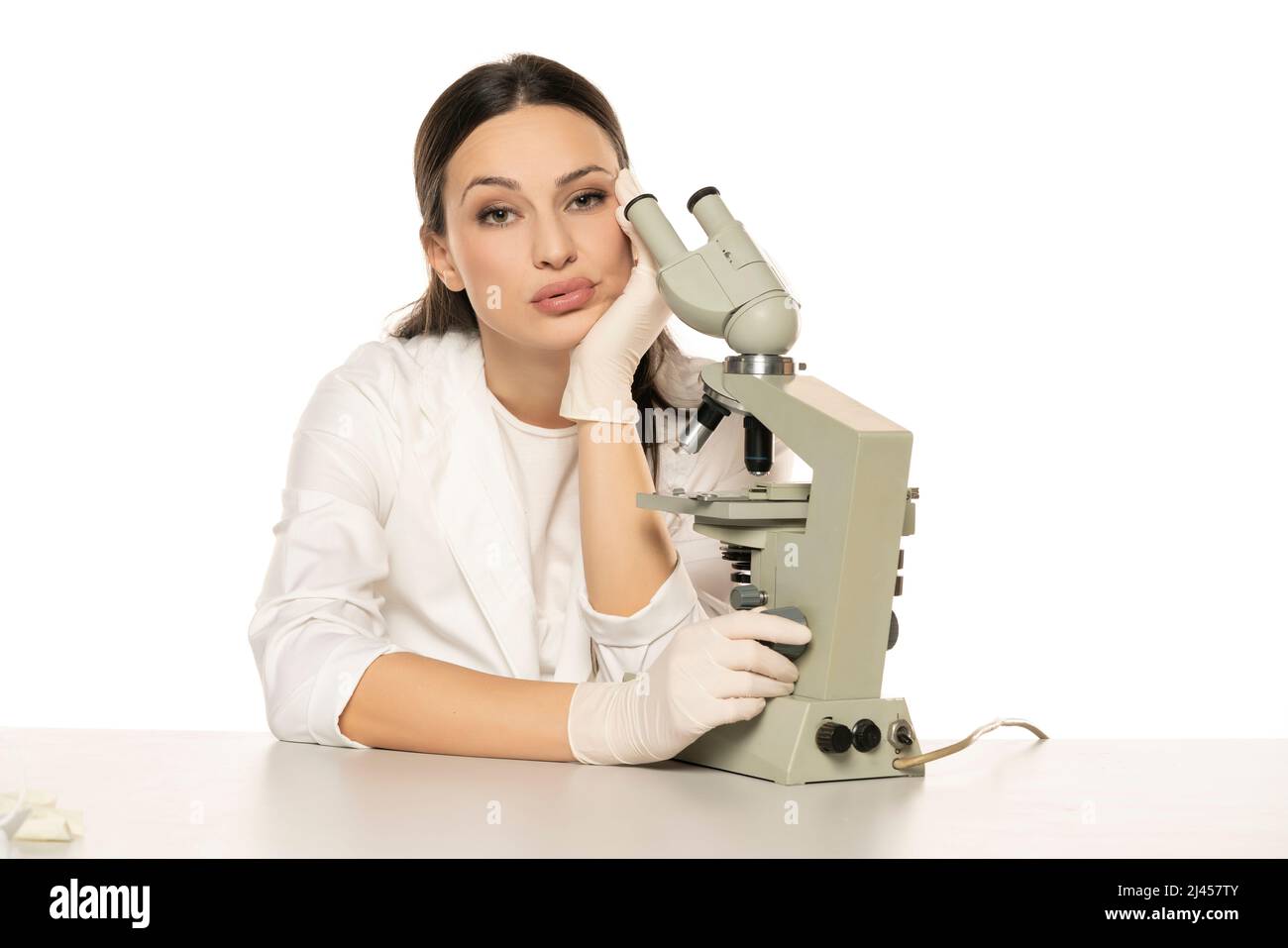 Portrait of bored female scientist with microscope on a white ...