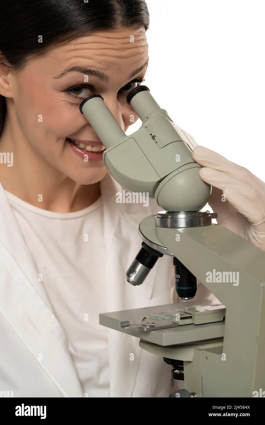 Happy female scientist looking through a microscope, close up, white ...