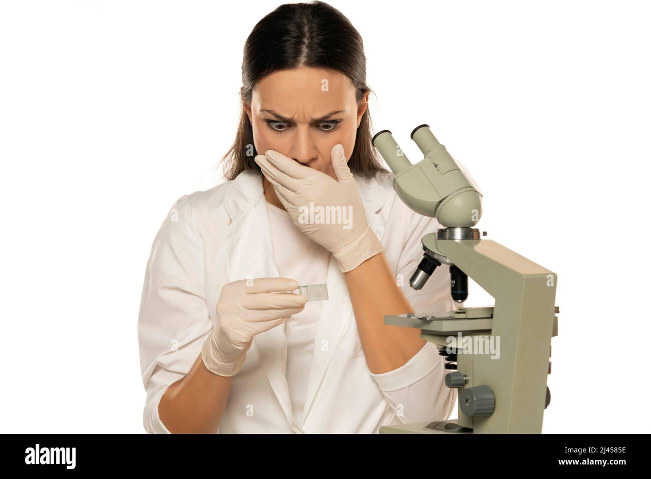 Portrait of shocked female scientist with microscope on a white ...