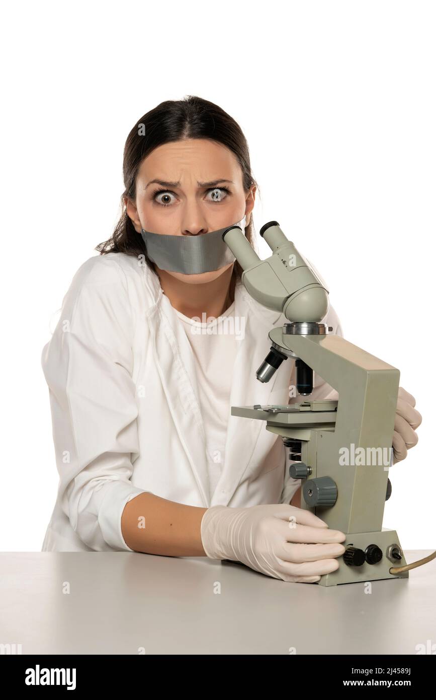 Portrait of confused female scientist with microscope, and tape over ...