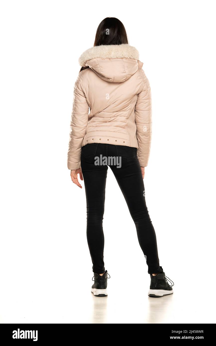 Rear view of a young woman in winter jacket, and black jeans posing on ...