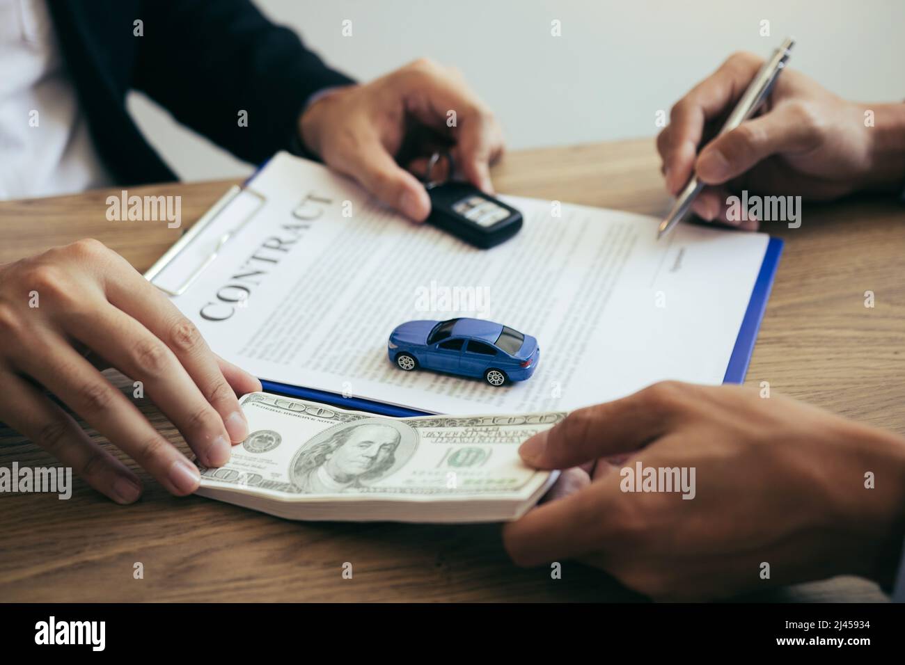 New car buyers are signing a contract with a car salesman at the ...