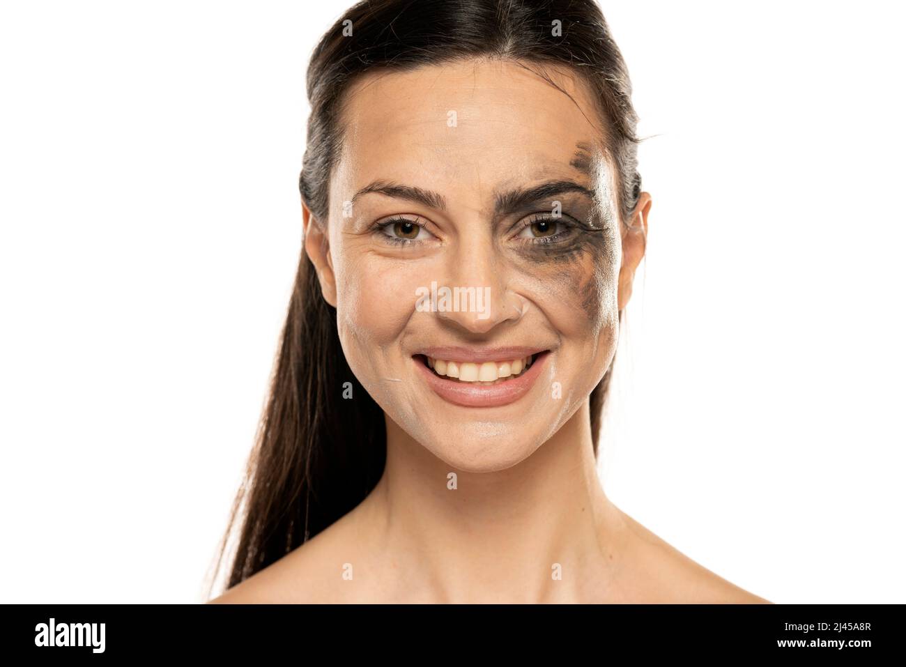 a young smiling woman posing with half face dirty and half cleansed of ...