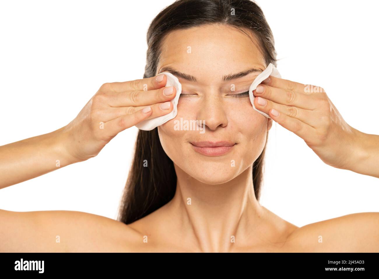 A young positive woman removing makeup with the cotton pads on white ...