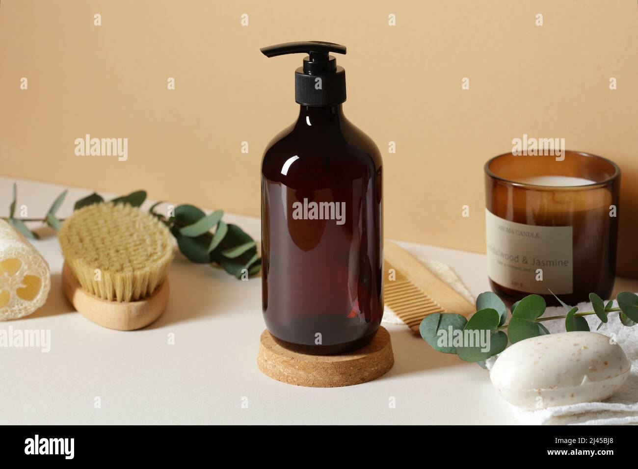 Amber glass shampoo bottle and bathroom accessories on table on beige ...