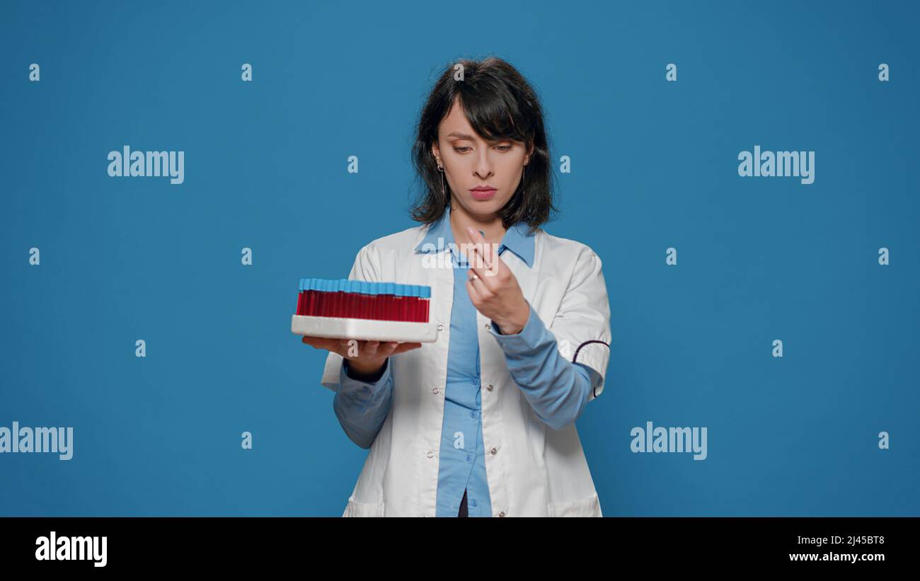 Microbiology specialist looking at test tubes with liquid samples on ...