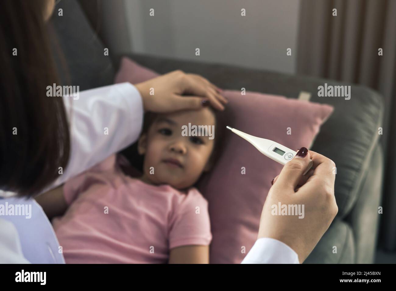 Asian female pediatrician is using a thermometer to measure fever for ...