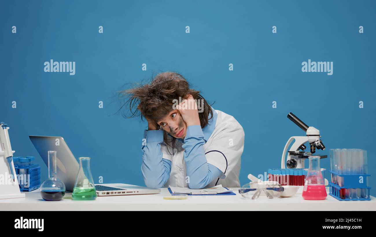 Amusing crazy scientist working on laptop and acting insane, doing ...