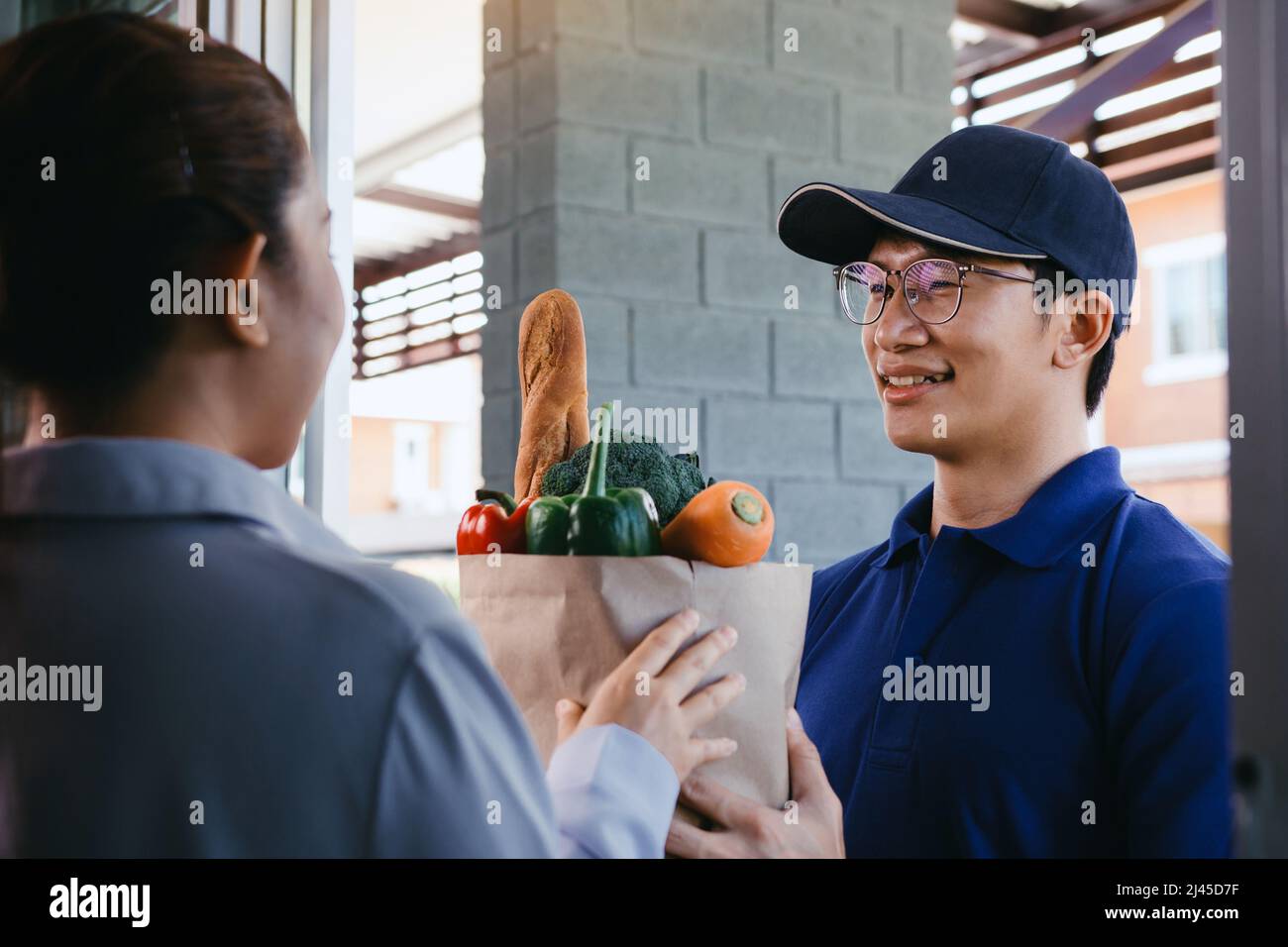 Delivery of an asian man handling a bag of food to a female customer at ...