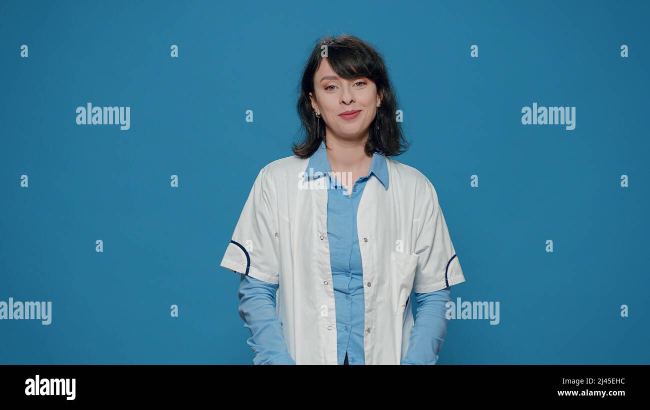 Portrait of woman scientist crossing arms over blue background, wearing ...