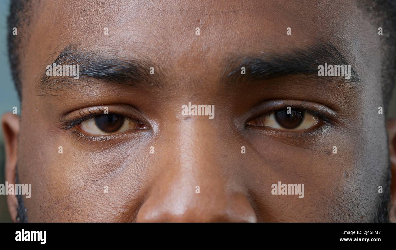 Macro shot of young man showing brown eyes on camera, blinking and ...