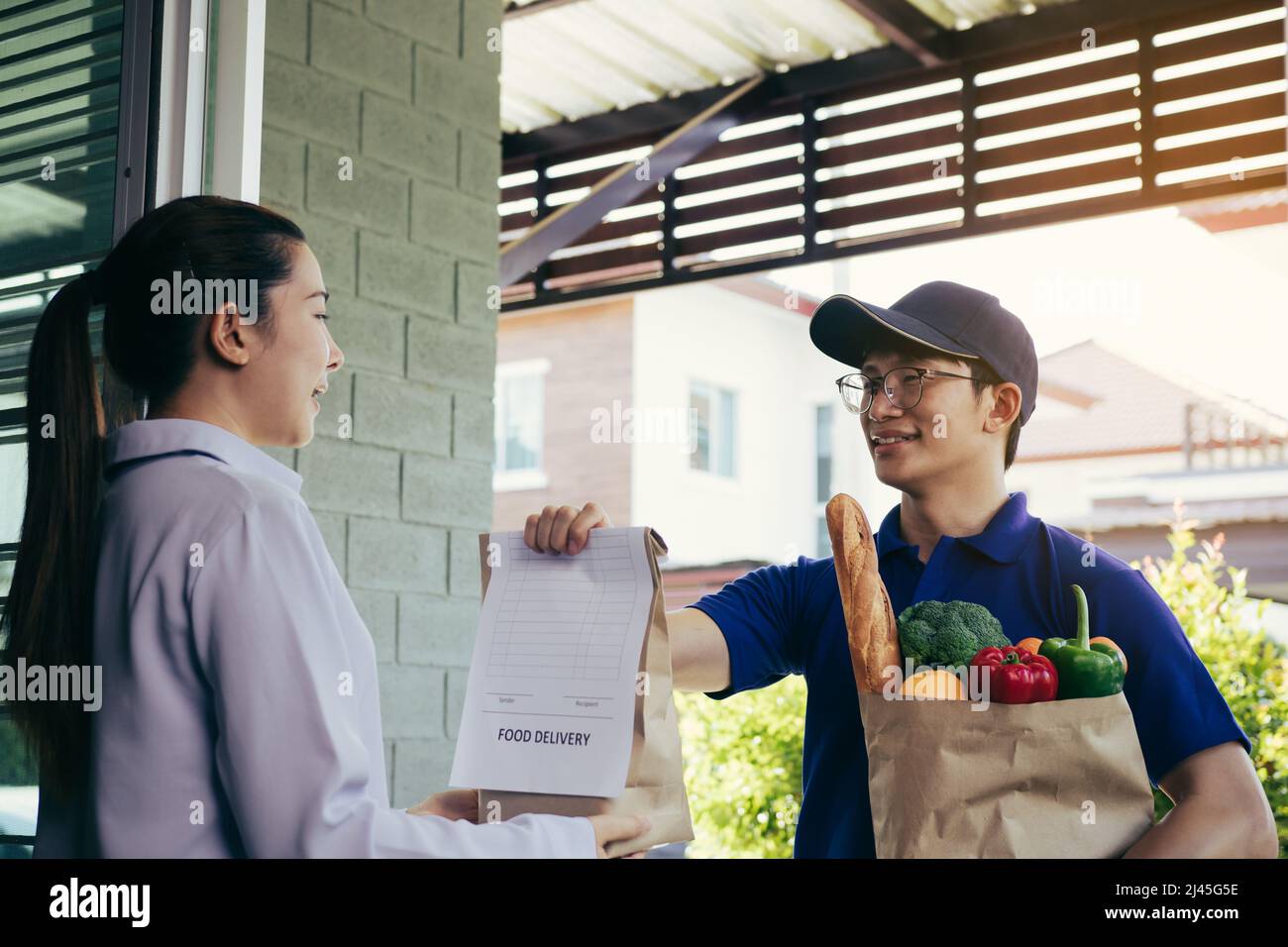 Supermarket food delivery staff deliver bags to female customers in ...