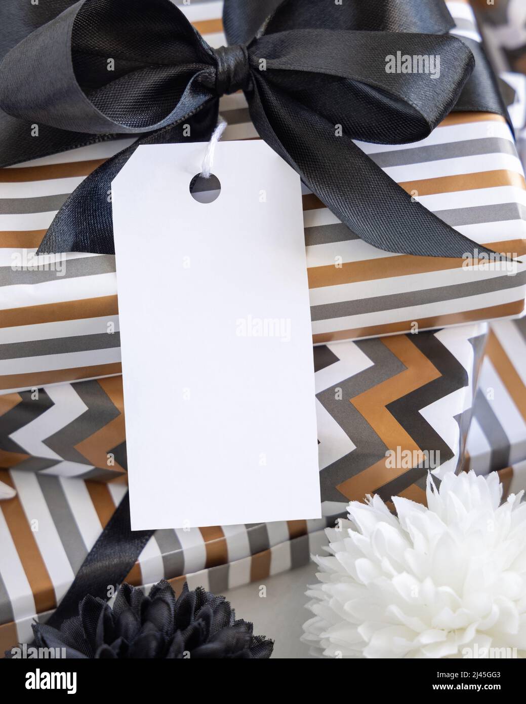 Present with blank vertical gift tag and black bow close up. Gift boxes ...