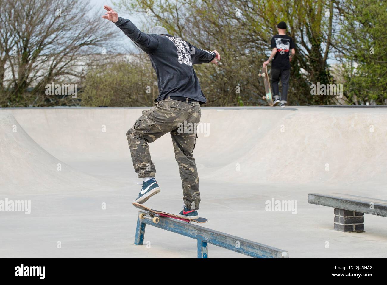 A mature male skateboarder performing a boardslide railslide trick at ...