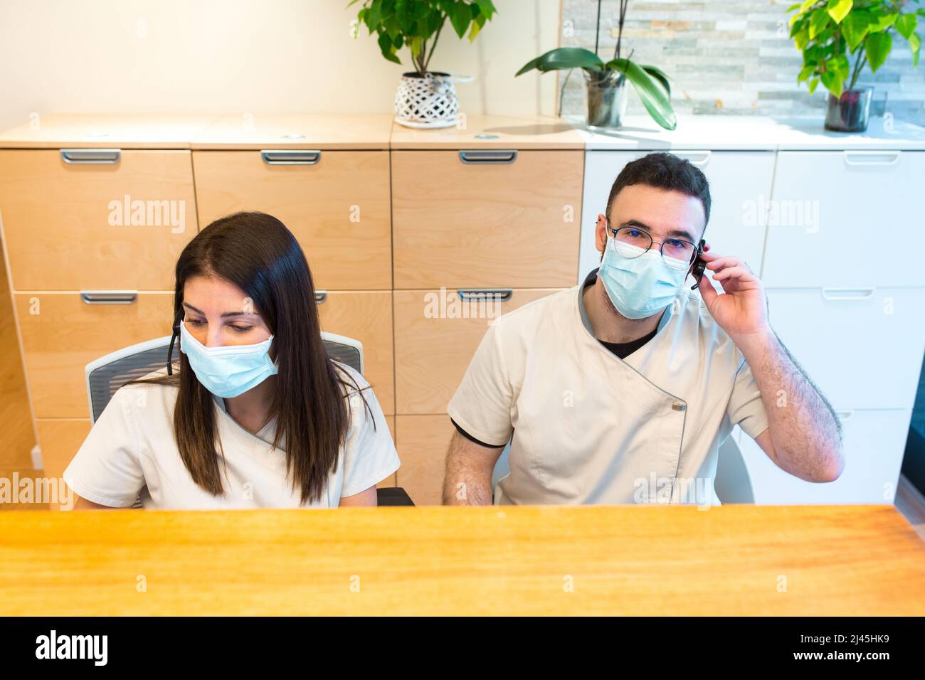 Two receptionists wearing a face mask while working at the reception ...
