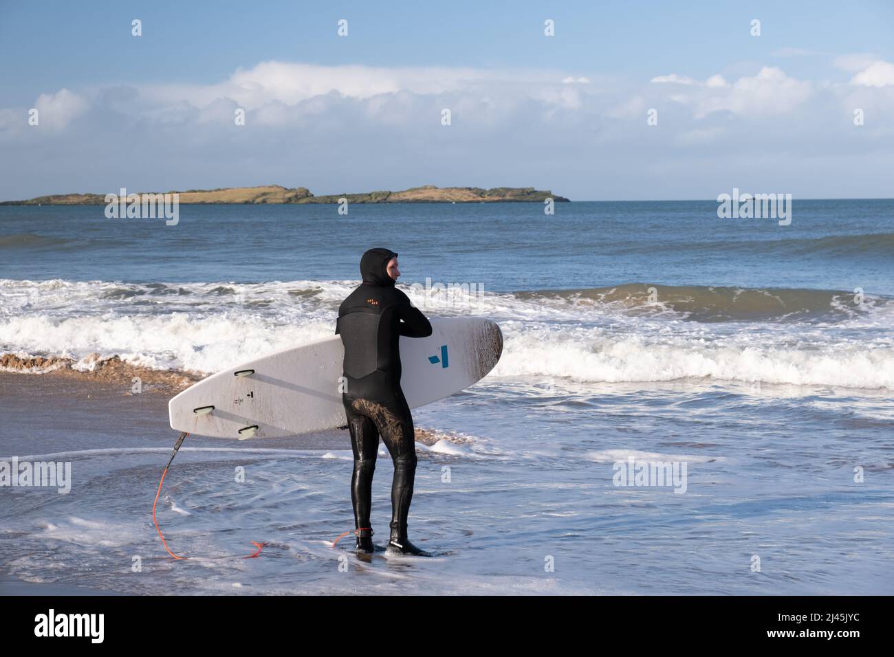 Surfer holding surf board wearing wetsuit getting ready to tackle the ...