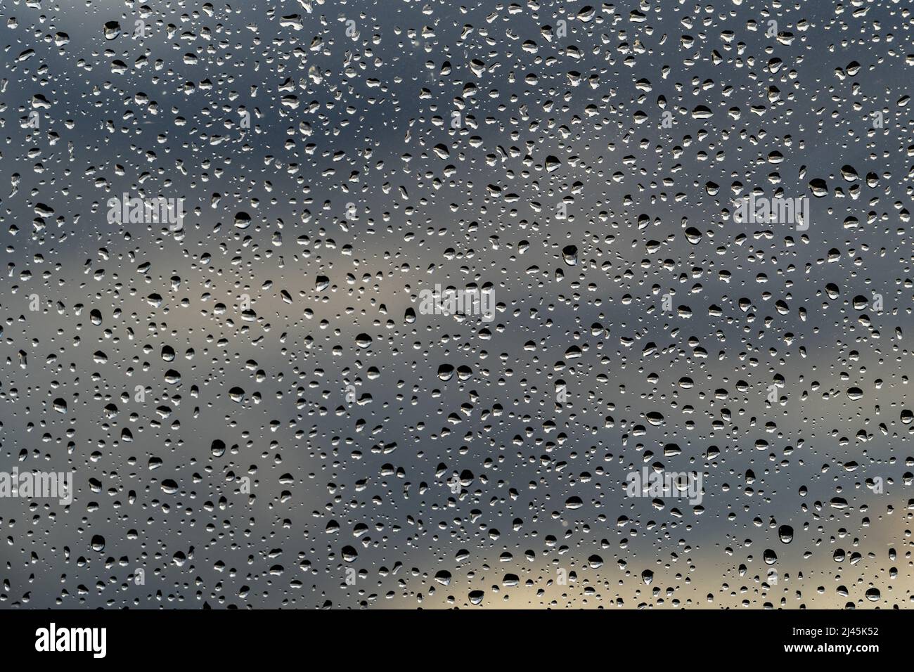 raindrops on a window pane with blurred dark clouds in the background Stock Photo - Alamy