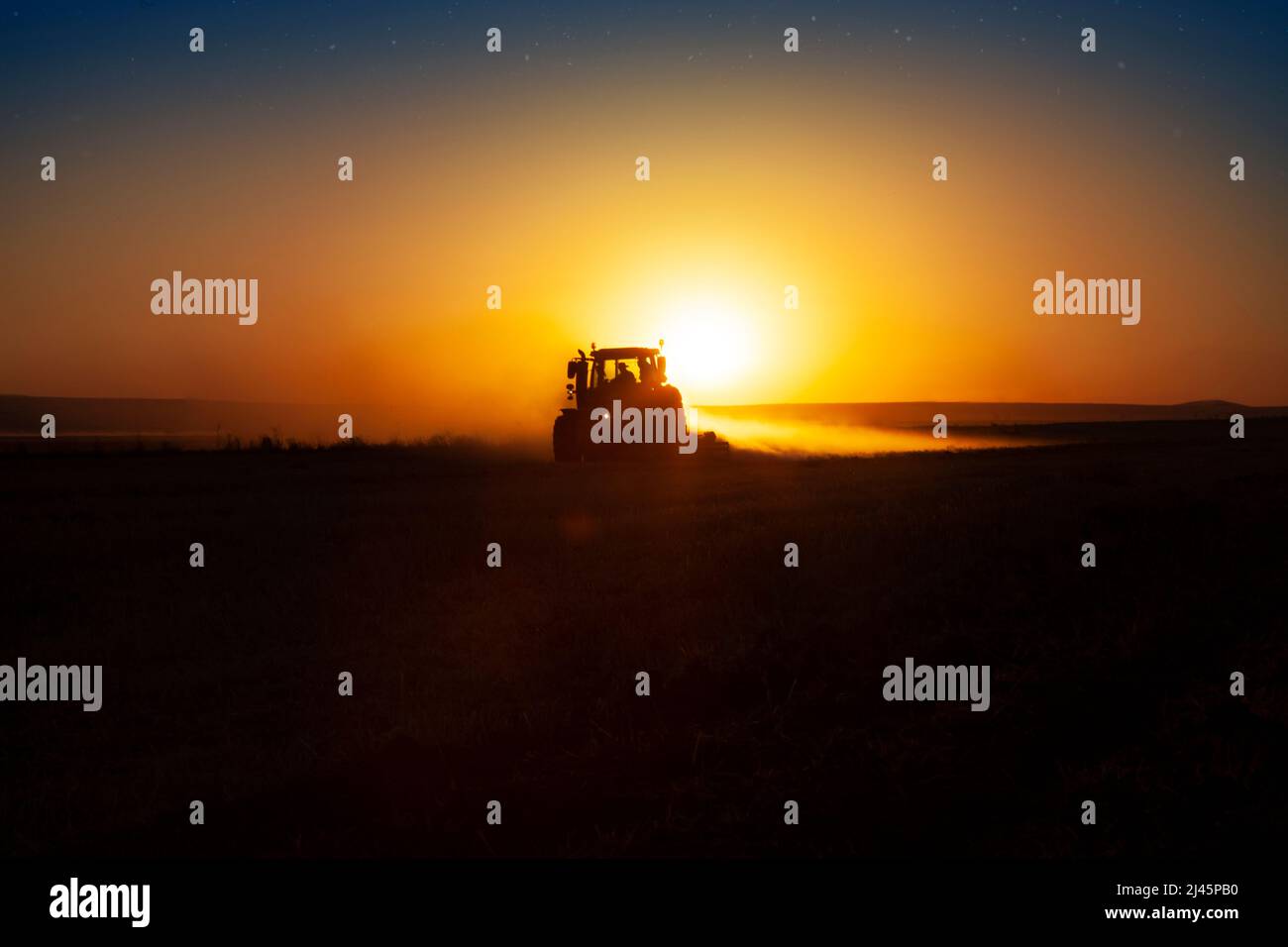 Tractor in sunset, farmer ploughs a field with tractor in sunset. The ...